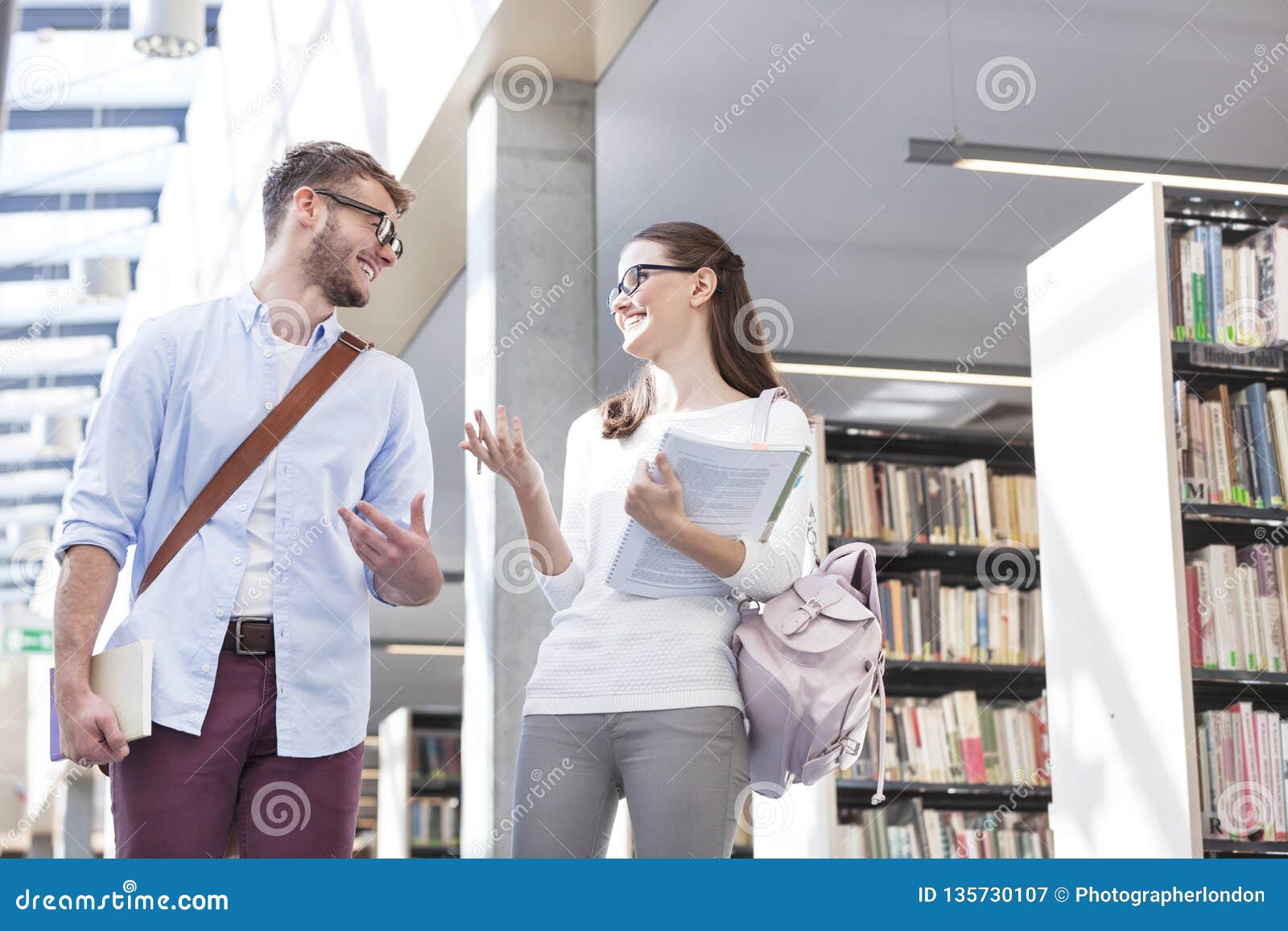 Happy Friends Discussing Over Books by Library at University Stock ...