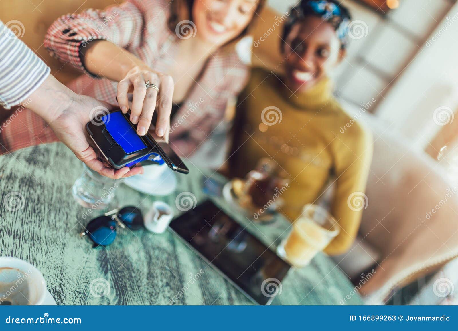 Friends Using Mobile Phone and Making Contactless Payment in a ...
