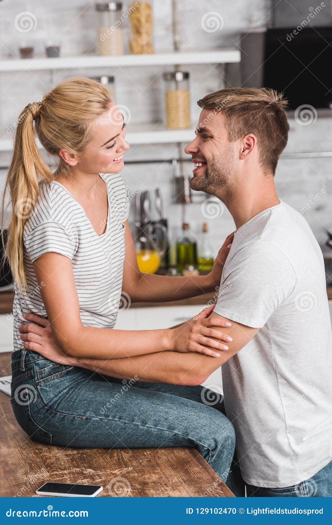Happy Girlfriend Sitting on Kitchen Counter and Looking at Boyfriend ...