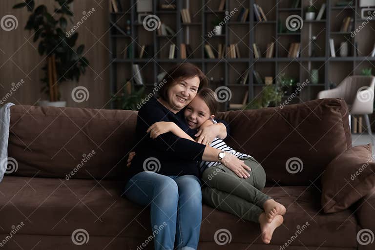 Happy Grandma Hugging And Cuddling Cute Granddaughter On Couch Stock