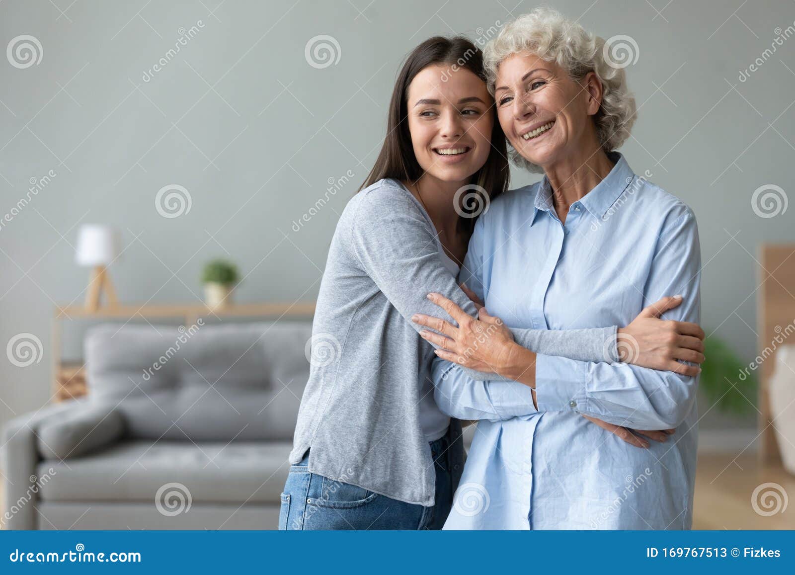 Happy Grandmother And Granddaughter Hugging Standing In Living Room