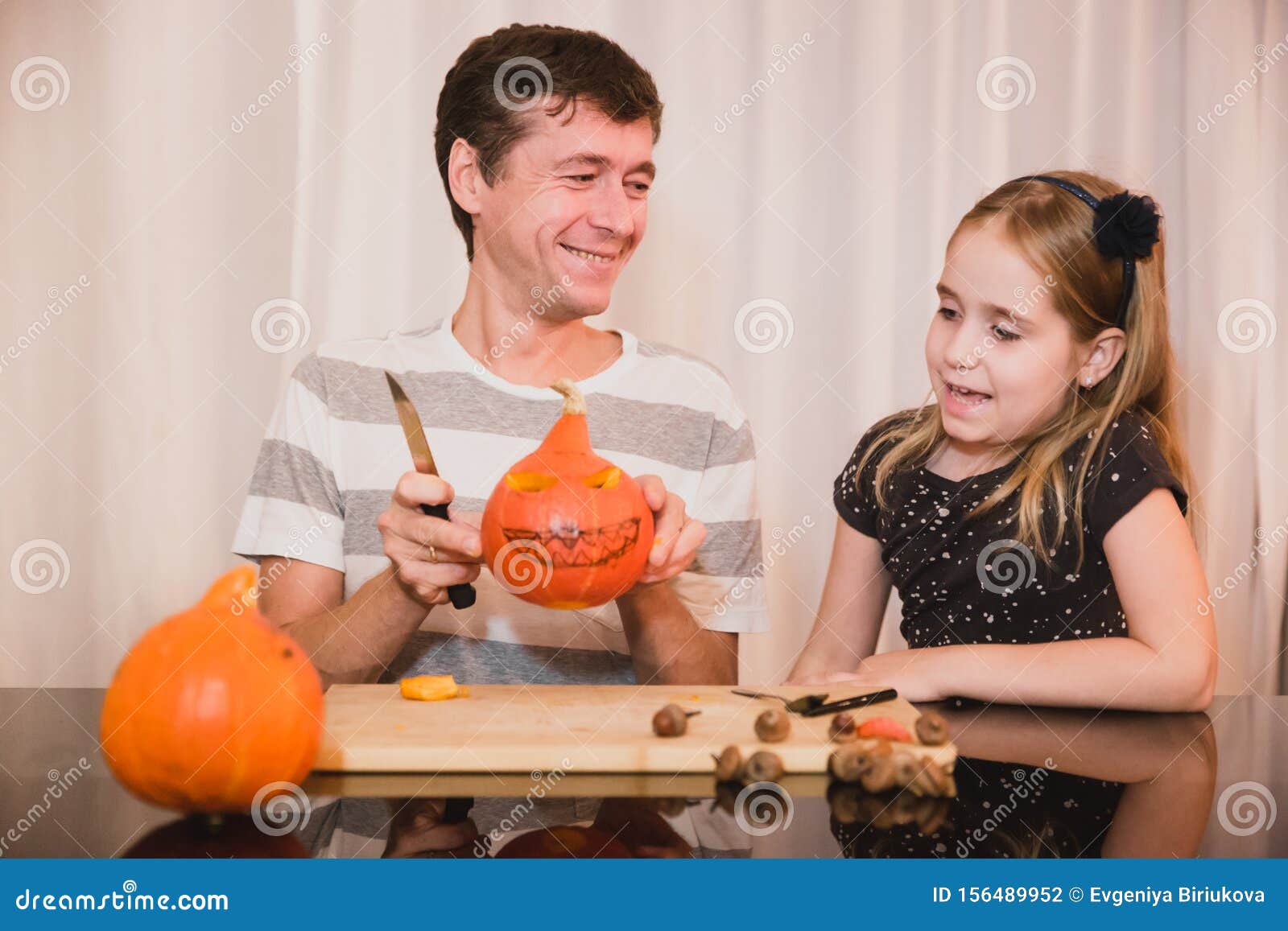 Happy Halloween Father And Daughter Carving Pumpkin For Halloween At