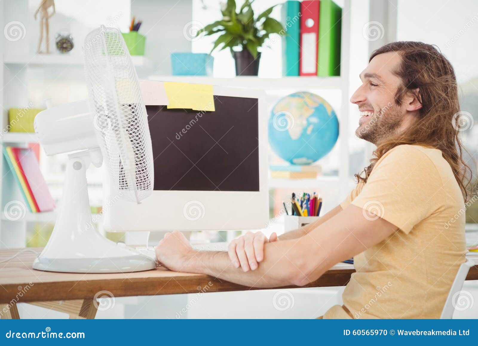 Happy Hipster Sitting by Electric Fan on Computer Desk Stock Photo ...