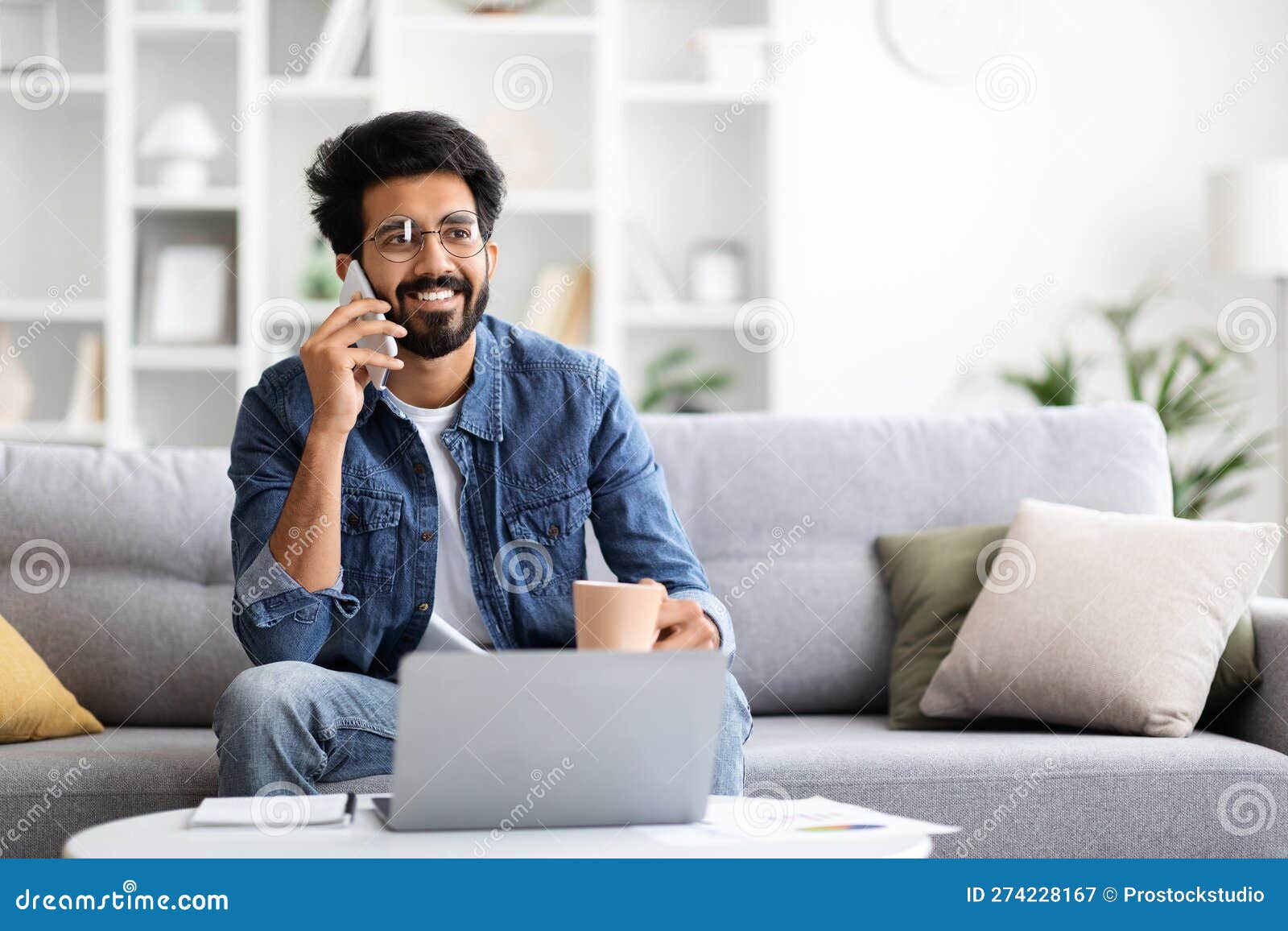 Happy Indian Freelancer Guy Talking on Cellphone and Using Laptop at ... Happy Indian Freelancer Guy Talking on Cellphone and Using Laptop at ...