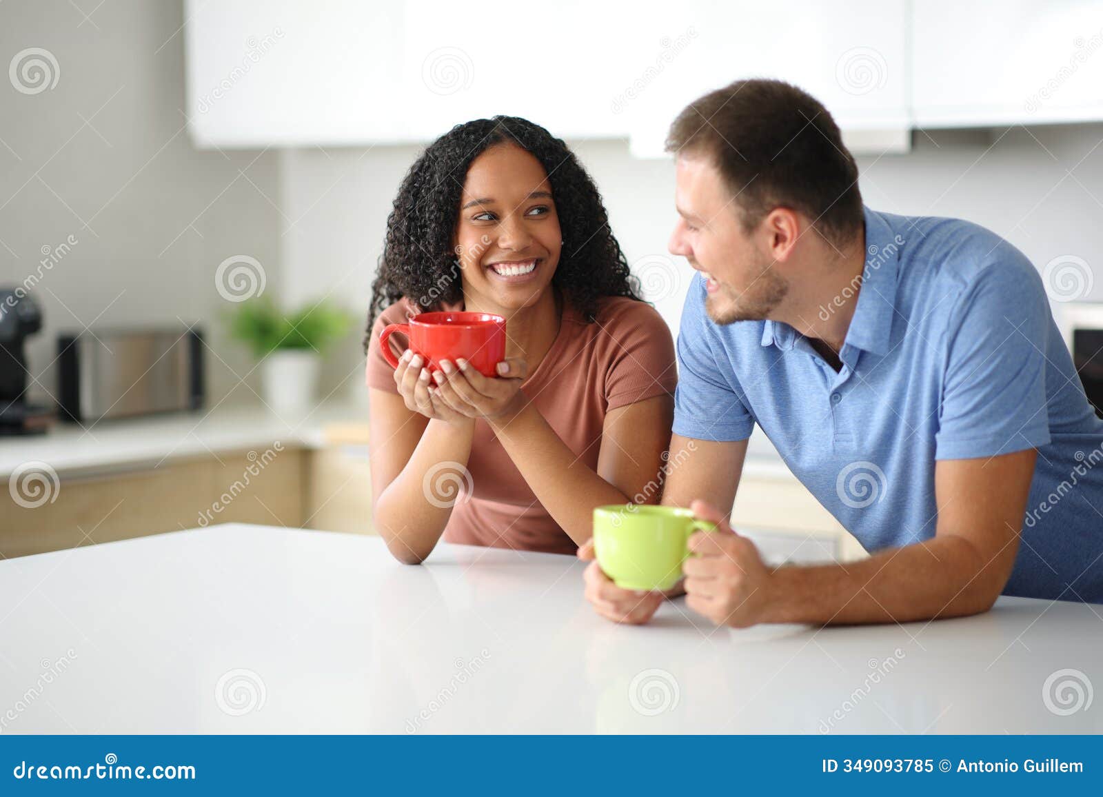 Happy Interracial Couple Talking and Drinking in the Kitchen Stock ...