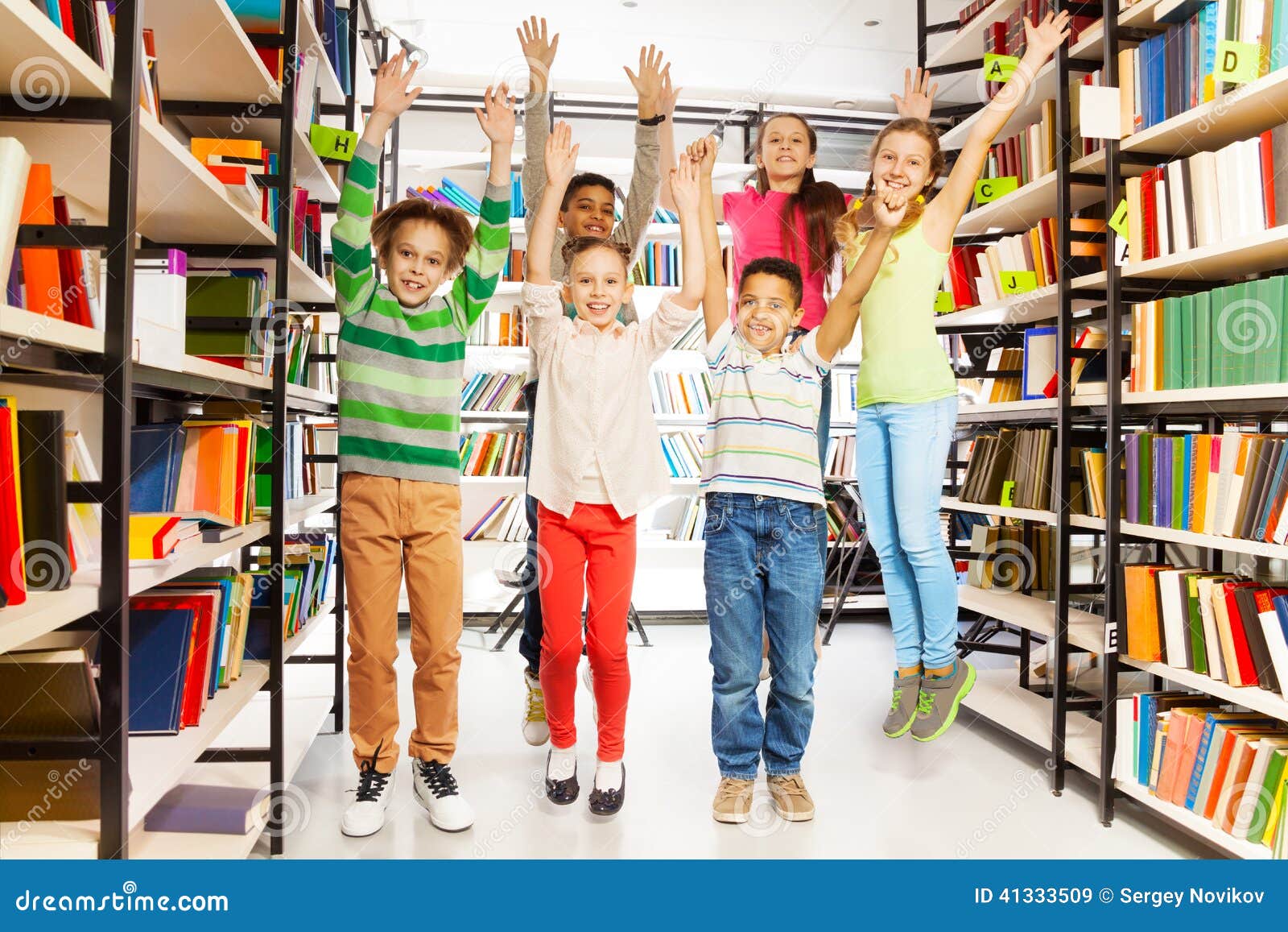 Happy Kids Jumping with Hands Up in the Library Stock Image - Image of ...