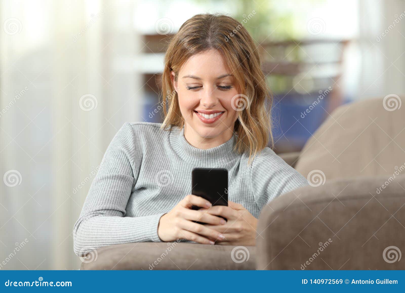 Happy Lady Texting on Phone on a Couch at Home Stock Image - Image of ...