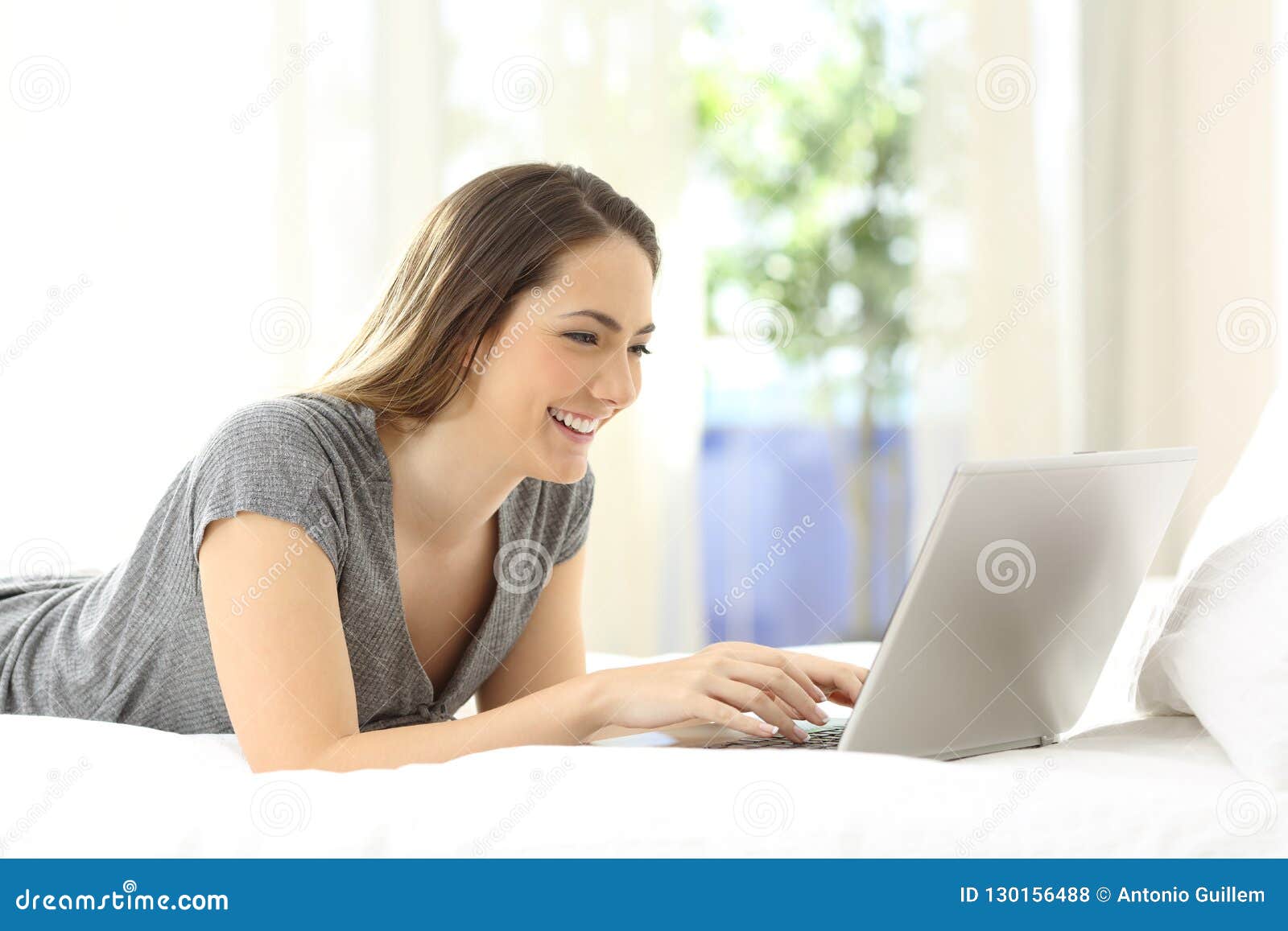Happy Lady Using a Laptop on the Bed at Home Stock Photo - Image of ...