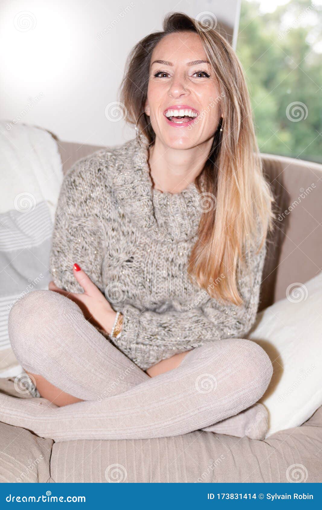Happy Laughing Young Woman Sitting on Sofa at Home Smiling Front House ... Happy Laughing Young Woman Sitting on Sofa at Home Smiling Front House ...