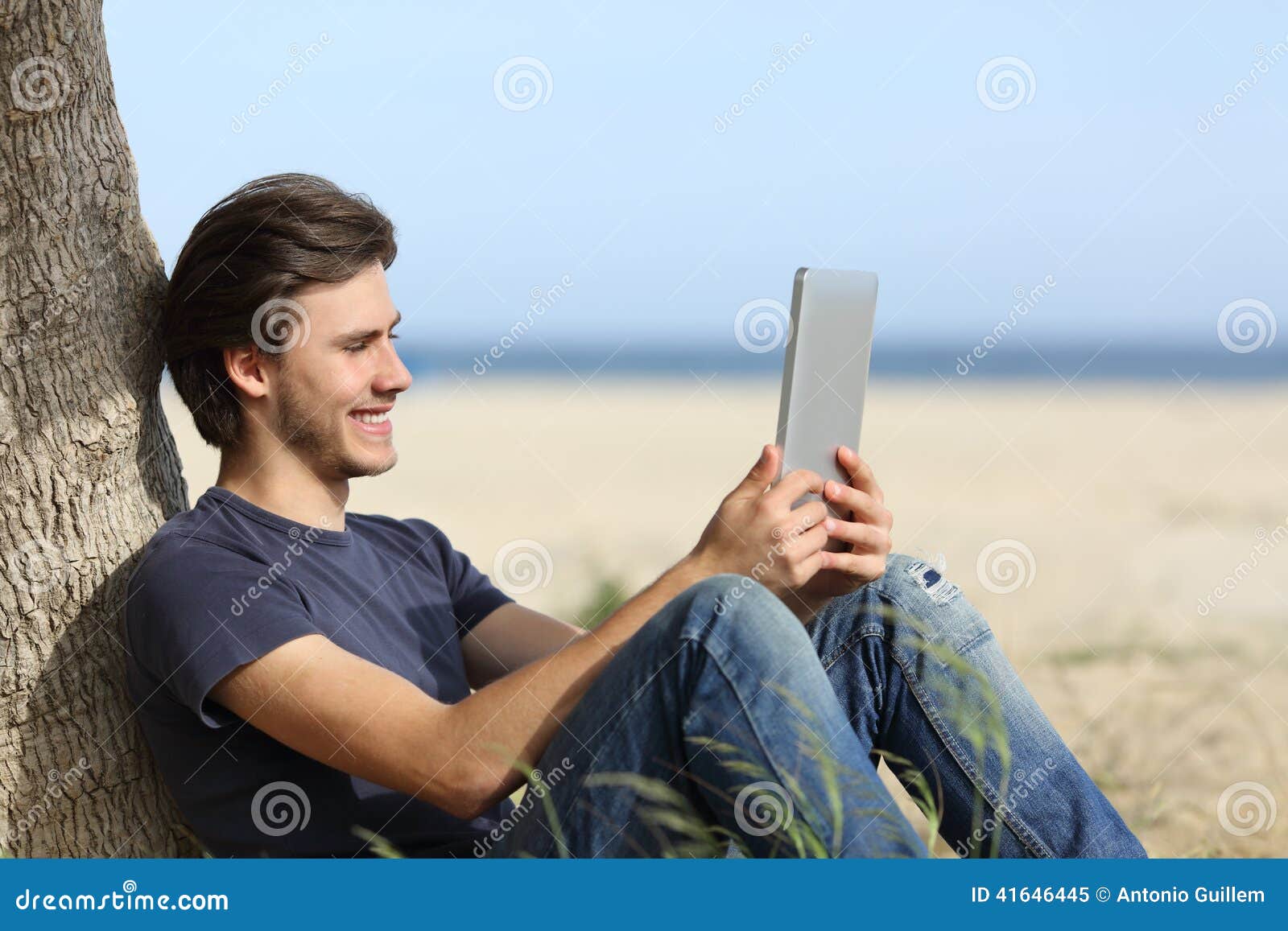 Happy Man Reading a Tablet Reader Sitting on the Beach Stock Image ...