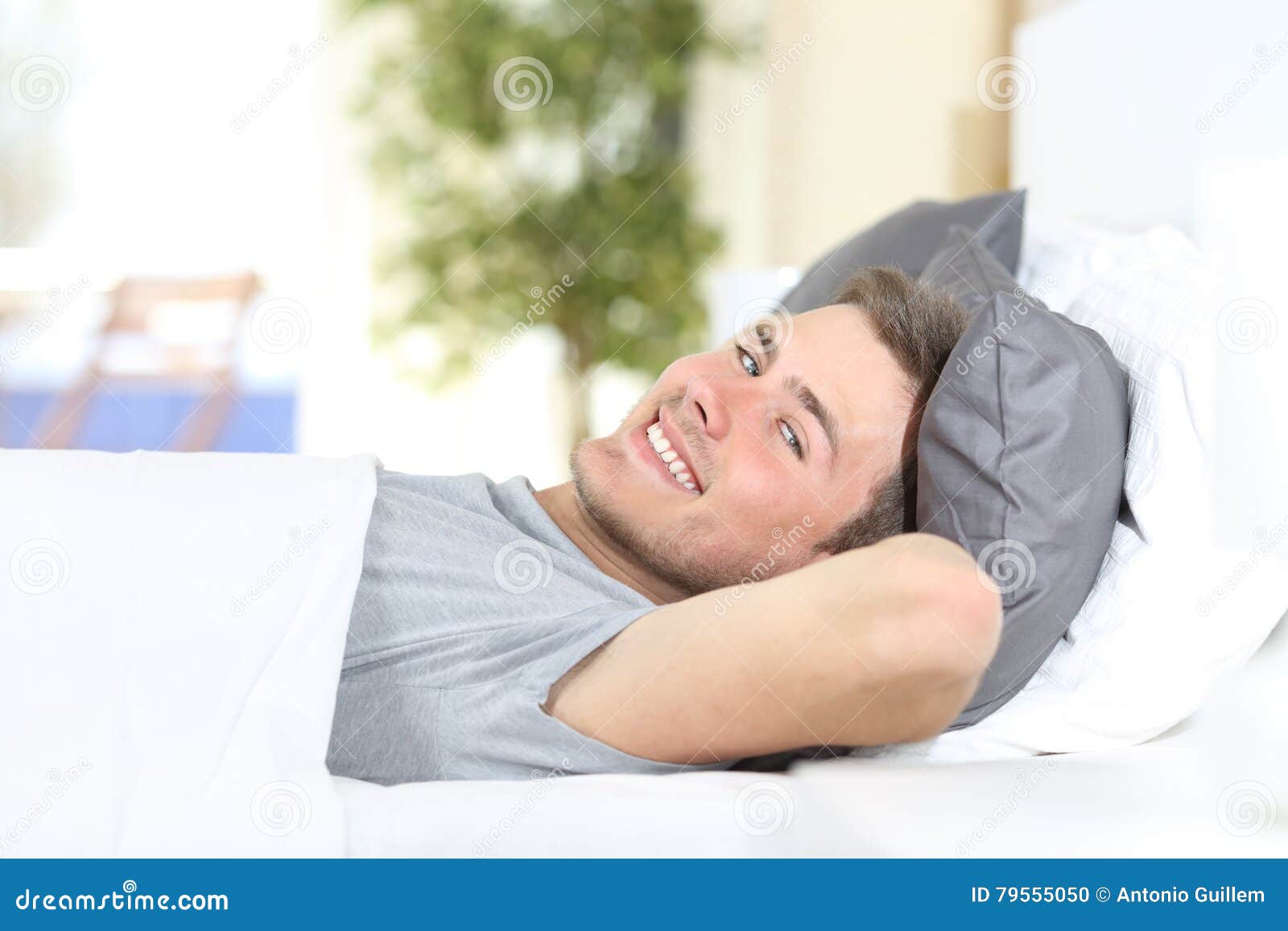 Happy man resting on a bed stock photo. Image of accommodation - 79555050