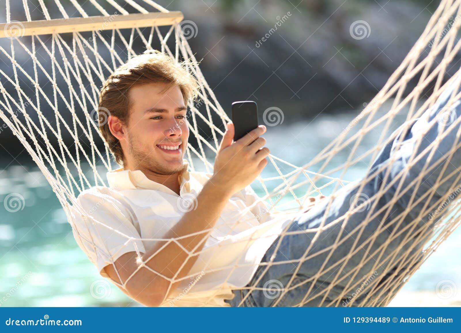 Happy Man Resting on a Hammock Using a Smart Phone Stock Image - Image ...