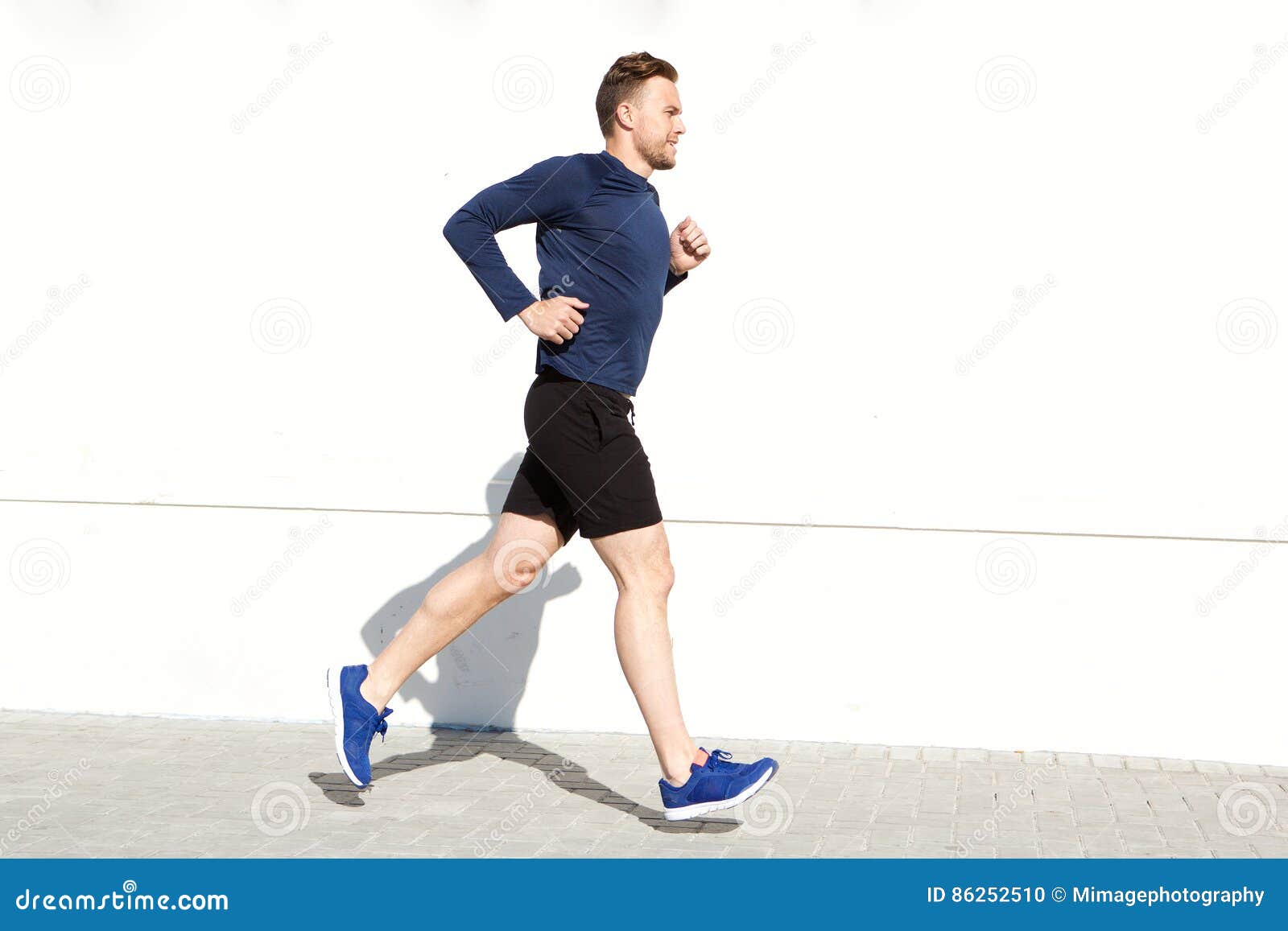 Happy Man Running Outside Against White Wall Stock Photo - Image of ...