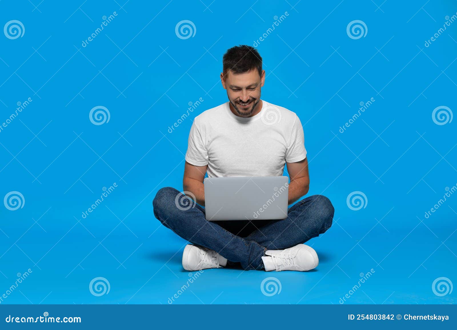 Happy Man Sitting with Laptop on Light Blue Background Stock Photo ...