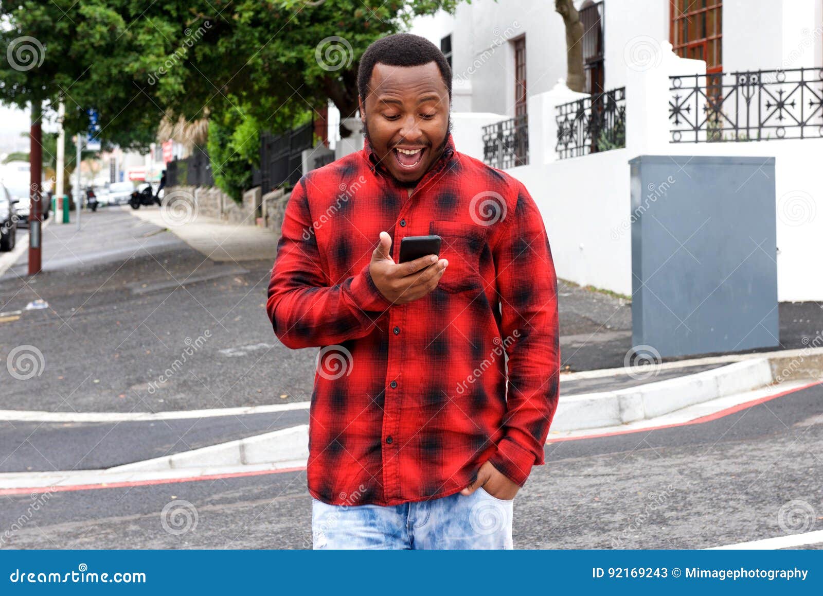Happy Man Standing Outside and Looking at Mobile Phone Stock Image ...