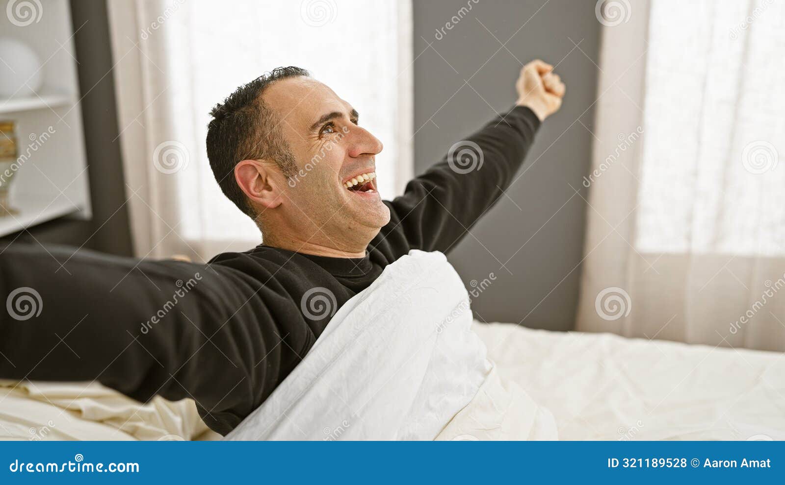 Happy Man Stretching in Bed with a Joyous Expression in a Bright ...