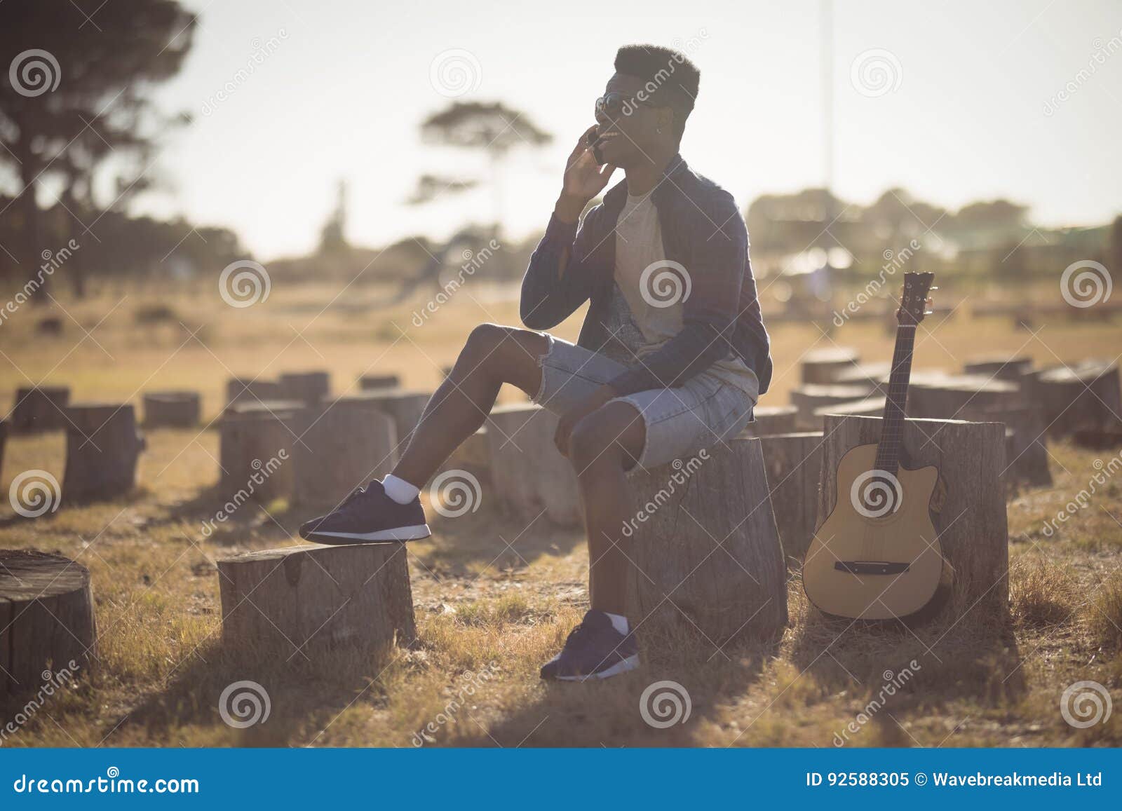 Happy Man Talking on Mobile Phone while Sitting on Tree Stump Stock ...