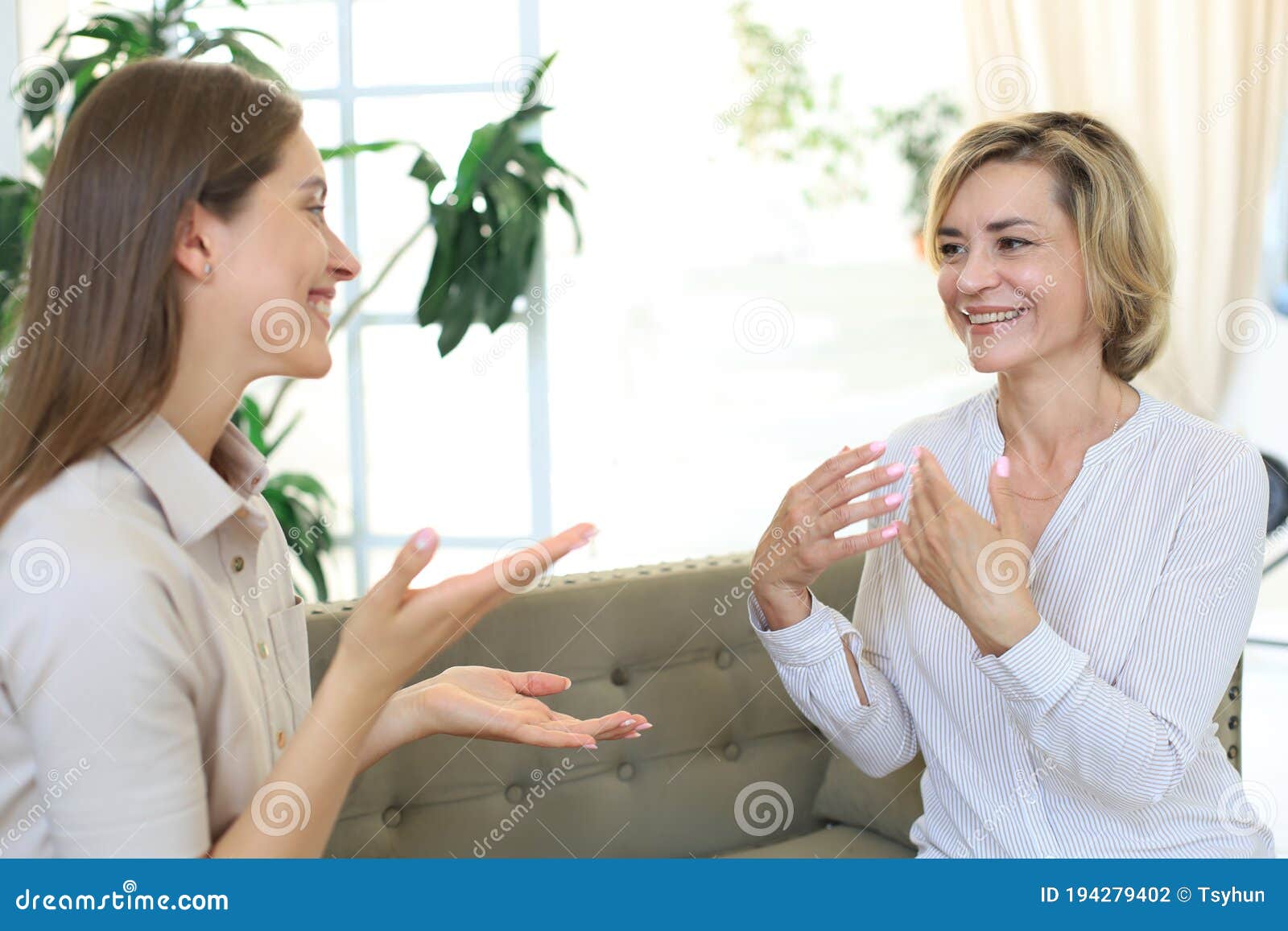 Happy Middle Aged Mother And Daughter Talking On Sofa In Living Room