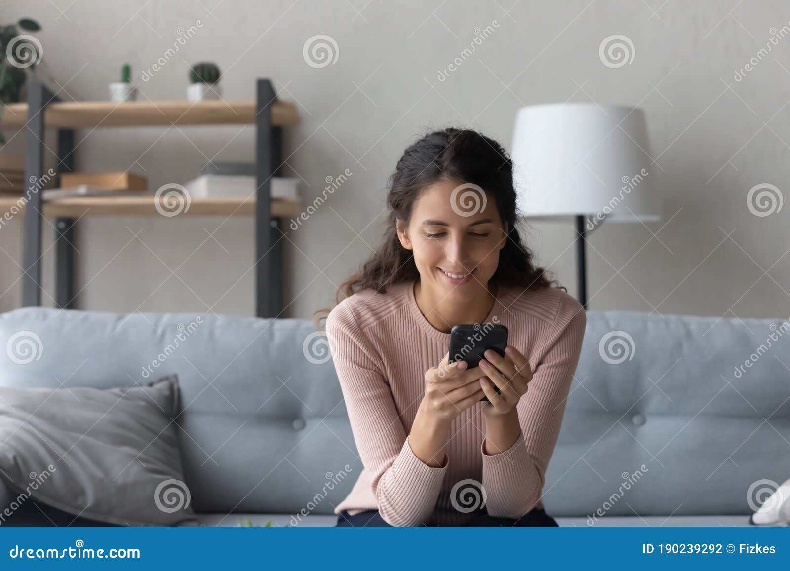 Happy Millennial Woman Browsing Internet On Cellphone At Home Stock