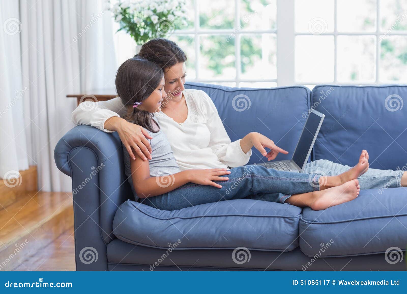 Happy Mother And Daughter Sitting On The Couch And Using Laptop Stock