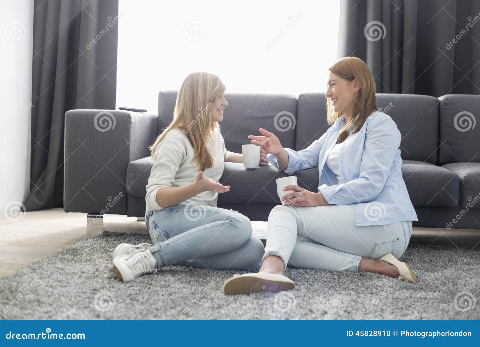 Happy Mother And Daughter Talking While Having Coffee In Living Room