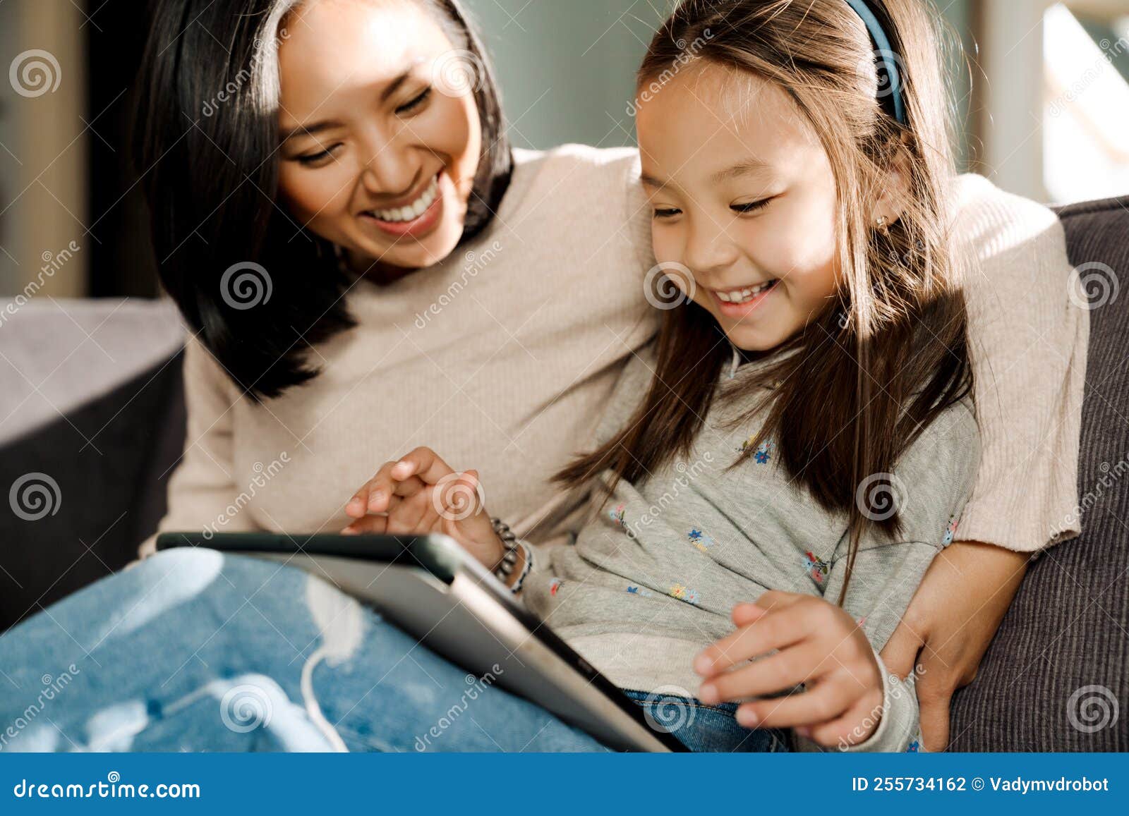 Happy Mother Using Tablet Computer while Hugging Her Daughter Stock ...