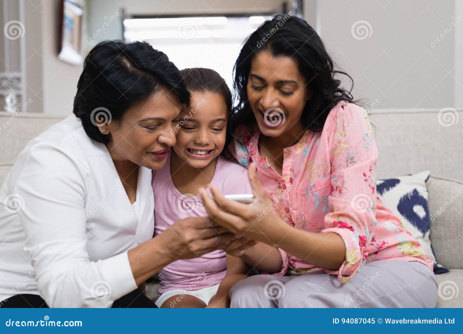 Happy Multi-generation Family Using Mobile Phone while Sitting Together ...