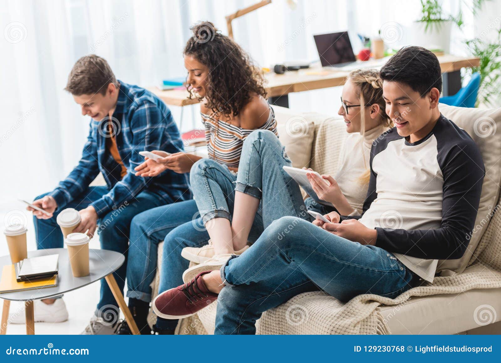 Happy Multicultural Teens Sitting on Sofa with Digital Stock Photo ...