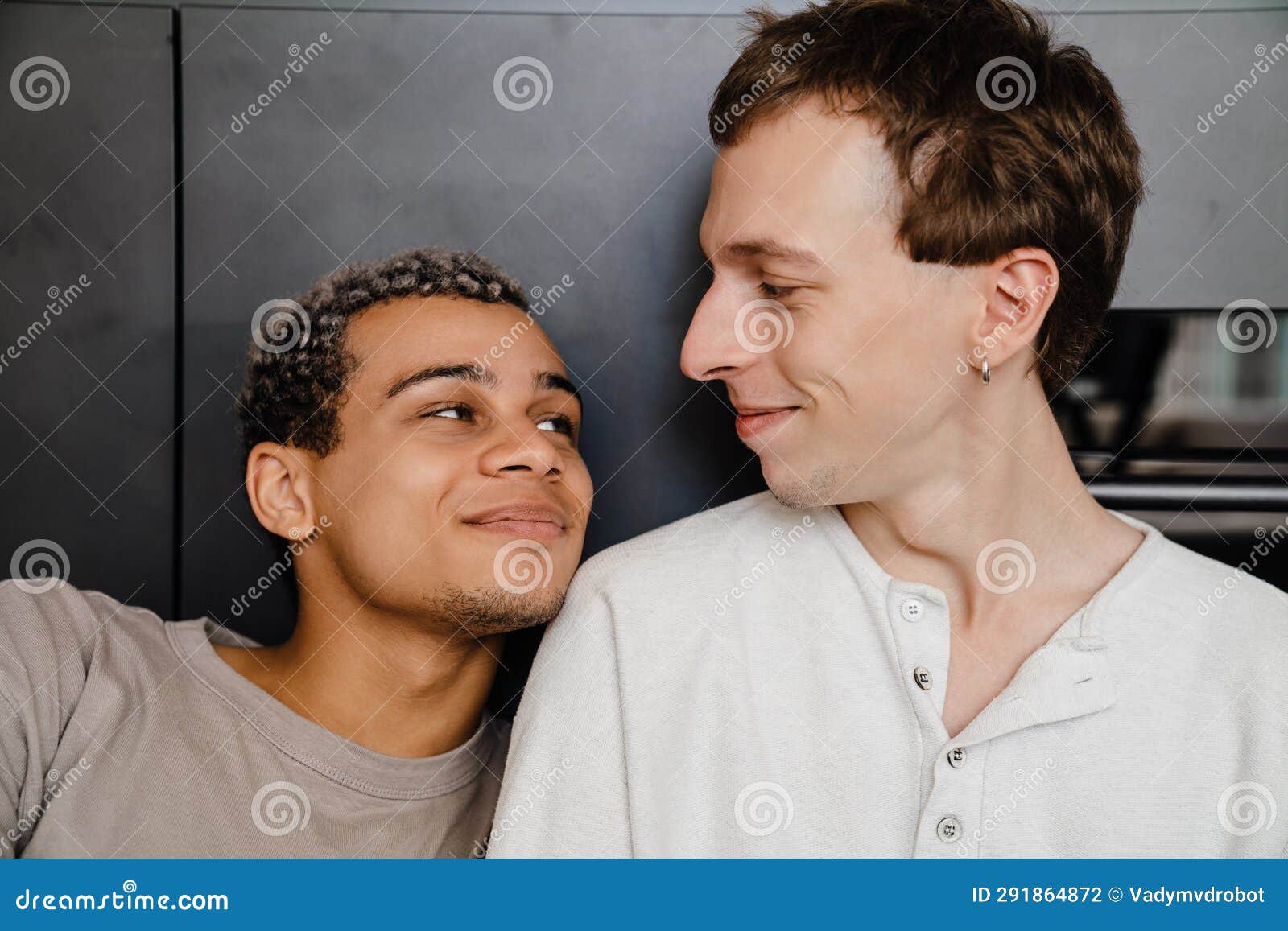 Happy Multiracial Gay Couple Smiling And Hugging Together At Home Stock