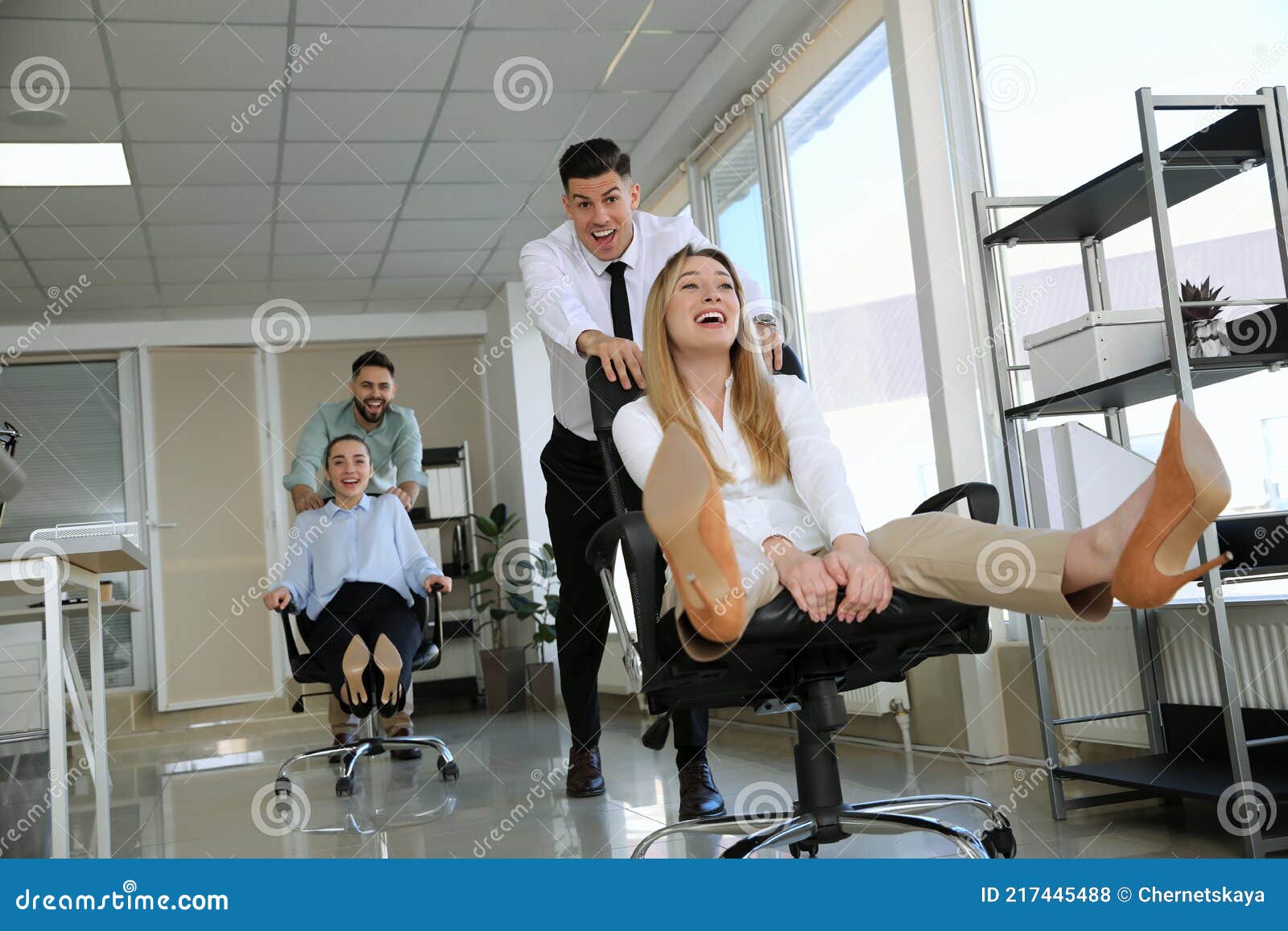 Happy Office Employees Riding Chairs at Workplace Stock Photo - Image ...