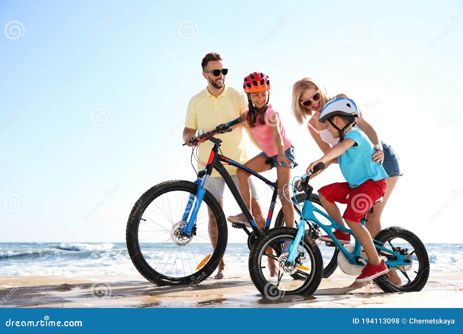 Happy Parents Teaching Children To Ride Bicycles on Beach Near Sea ... Happy Parents Teaching Children To Ride Bicycles on Beach Near Sea ...