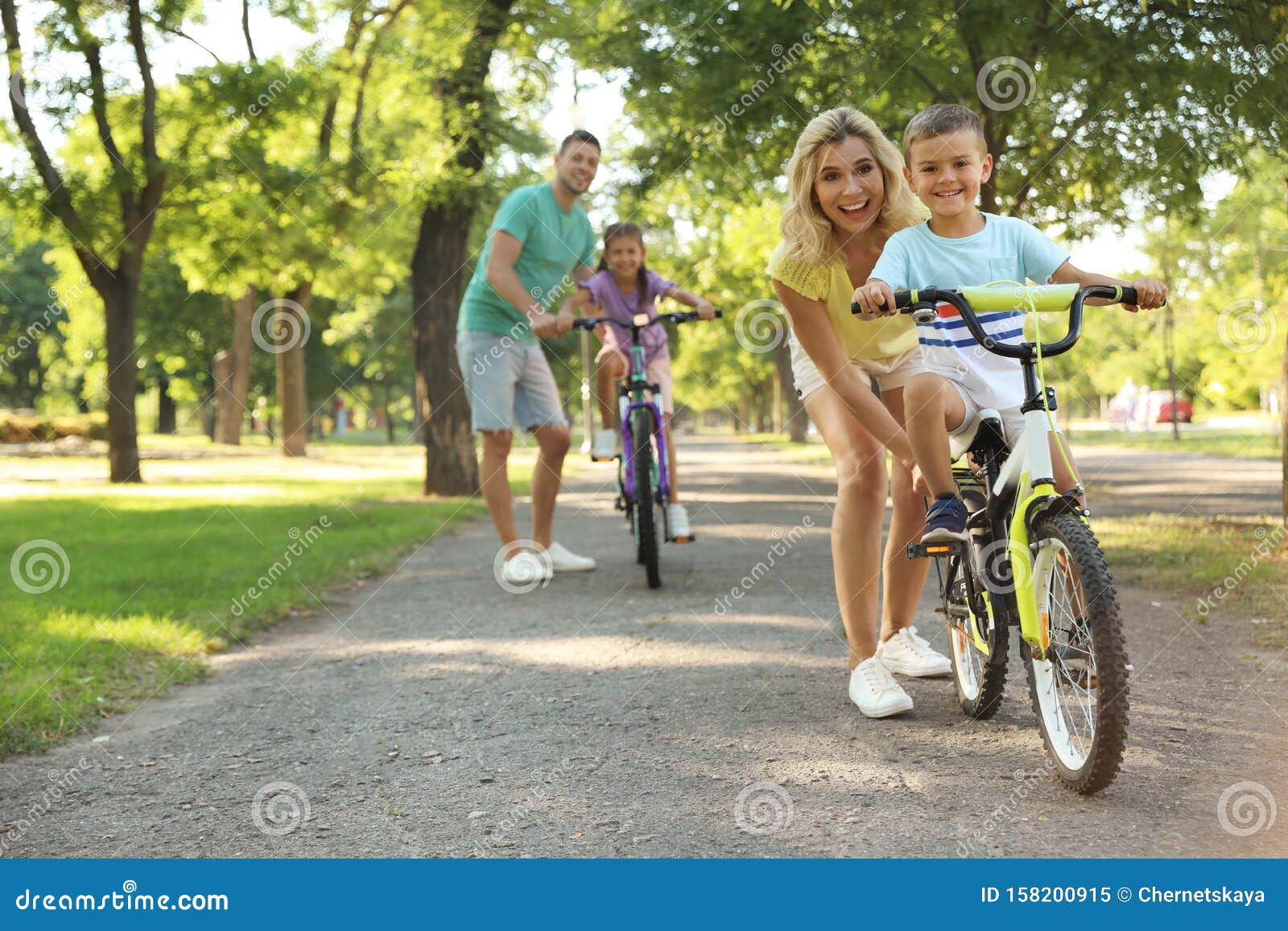 Happy Parents Teaching Their Children To Ride Bicycle in Stock Image ... Happy Parents Teaching Their Children To Ride Bicycle in Stock Image ...