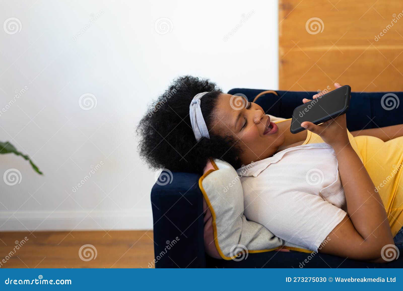 Happy Plus Size African American Woman Lying On Sofa And Talking On