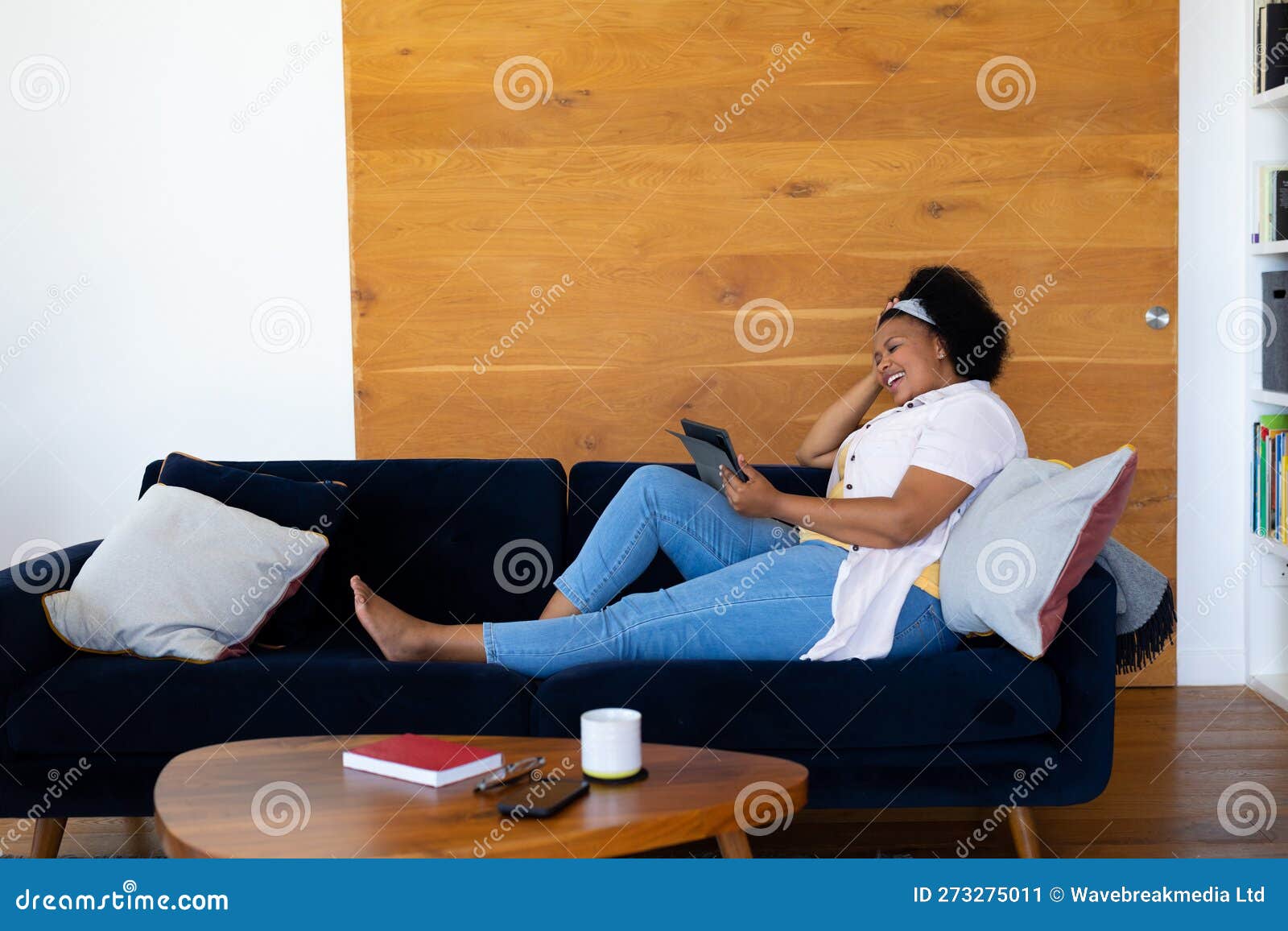 Happy Plus Size African American Woman Relaxing On Sofa Using Tablet