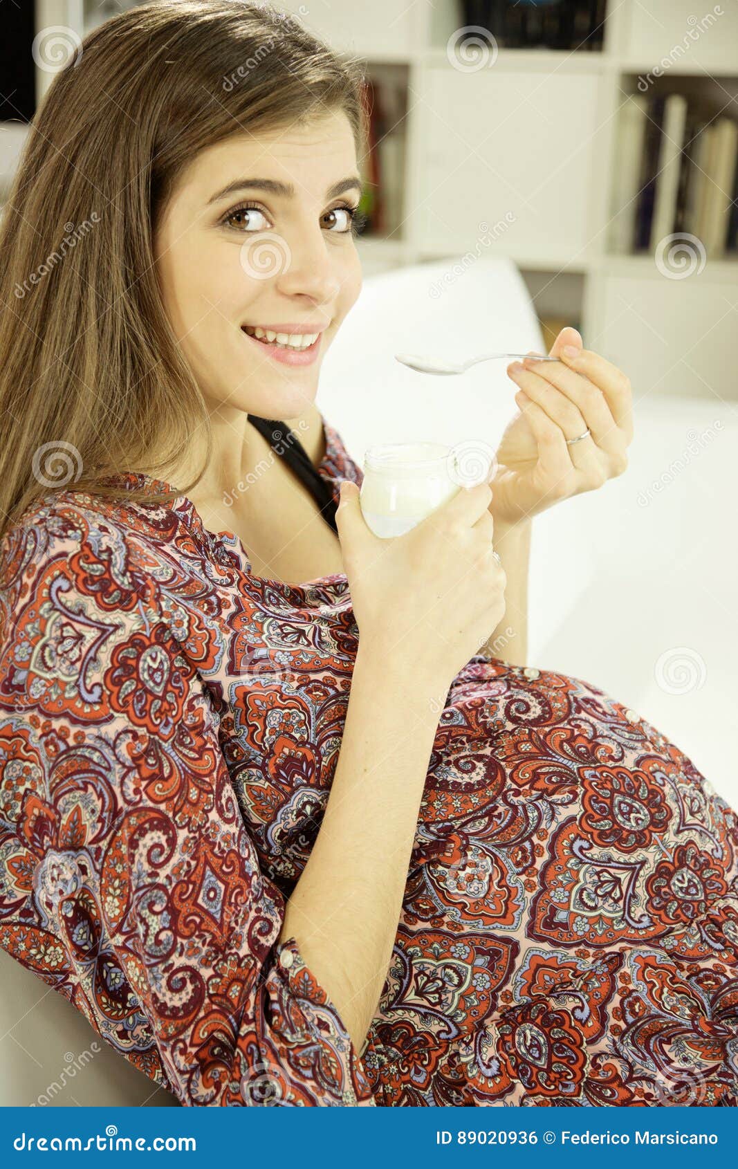 Happy Pregnant Woman Eating Chocolate Ice Cream At Home Looking Camera