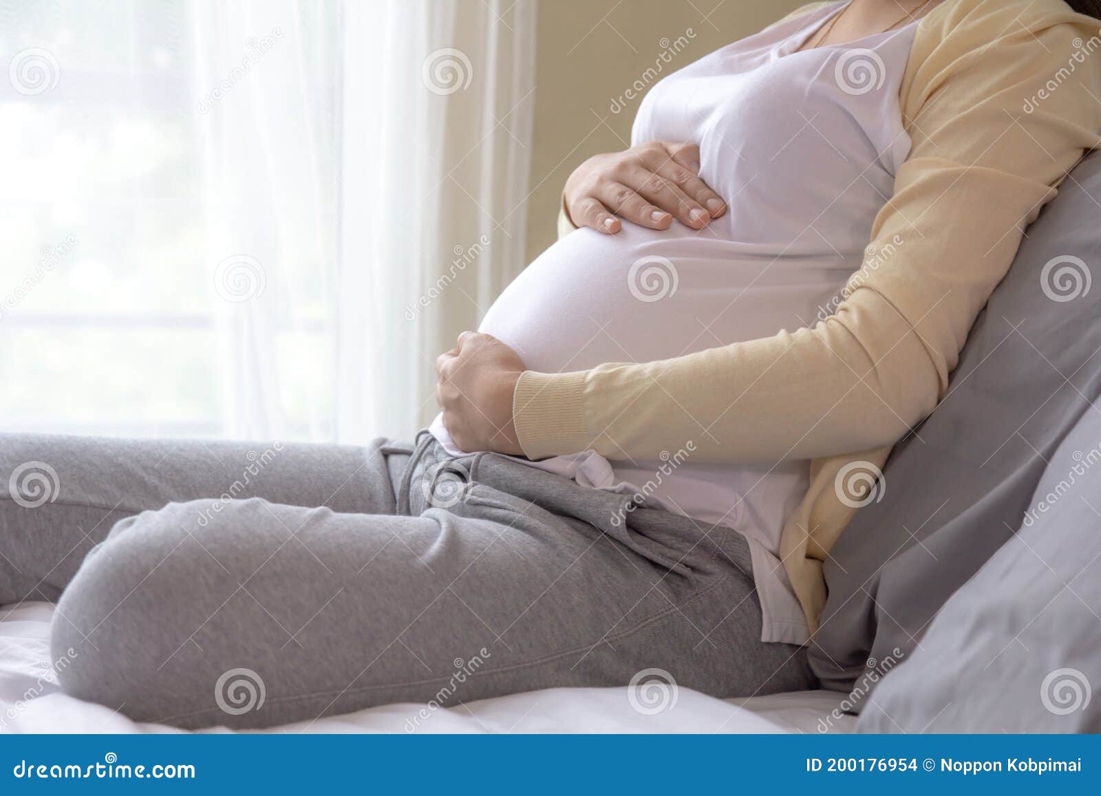 Happy Pregnant Woman Touching Belly Sitting In Bed At Home Close Up