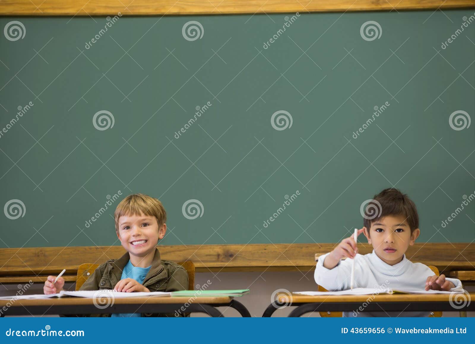 Happy Pupils Writing in Notepad at Desks Stock Photo - Image of ...