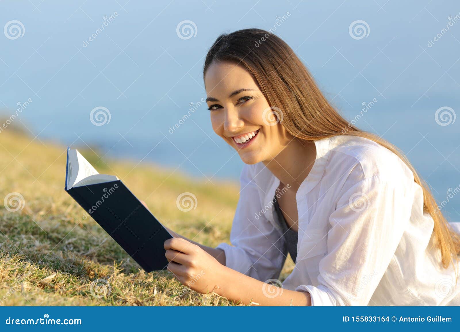 Happy Reader Holding a Book on the Grass Looks at You Stock Photo ...