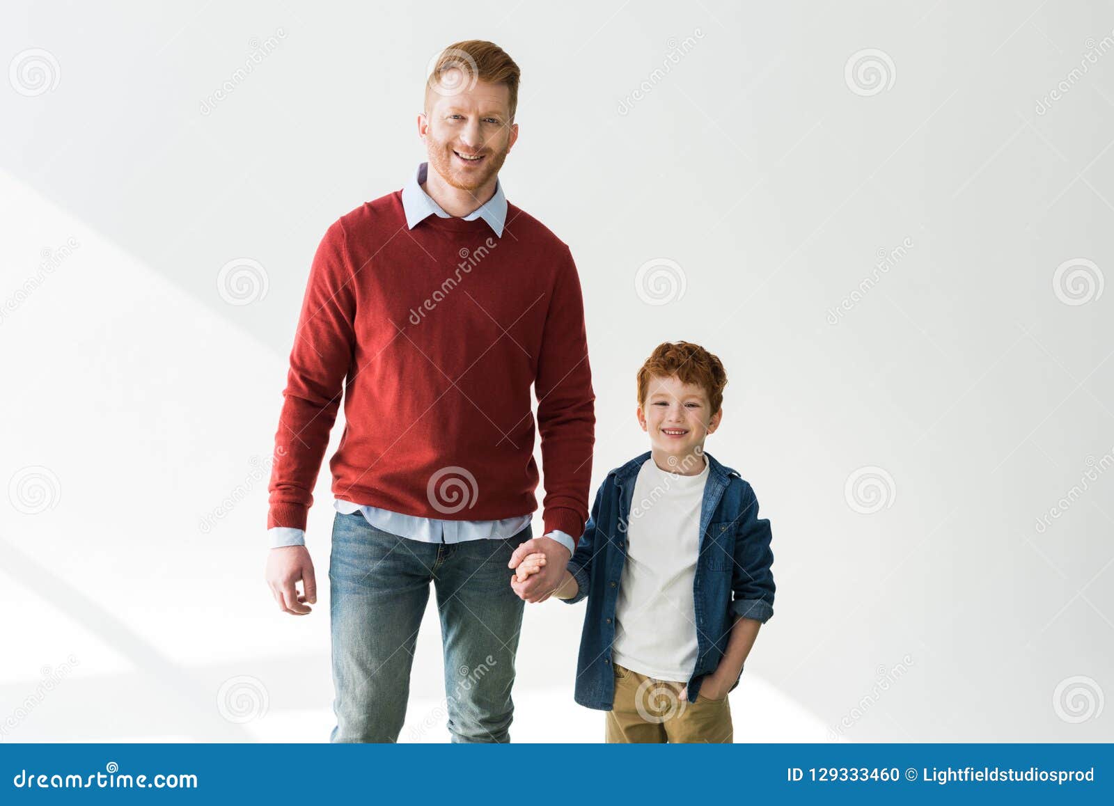 Happy Redhead Father And Son Holding Hands And Smiling At Camera Stock