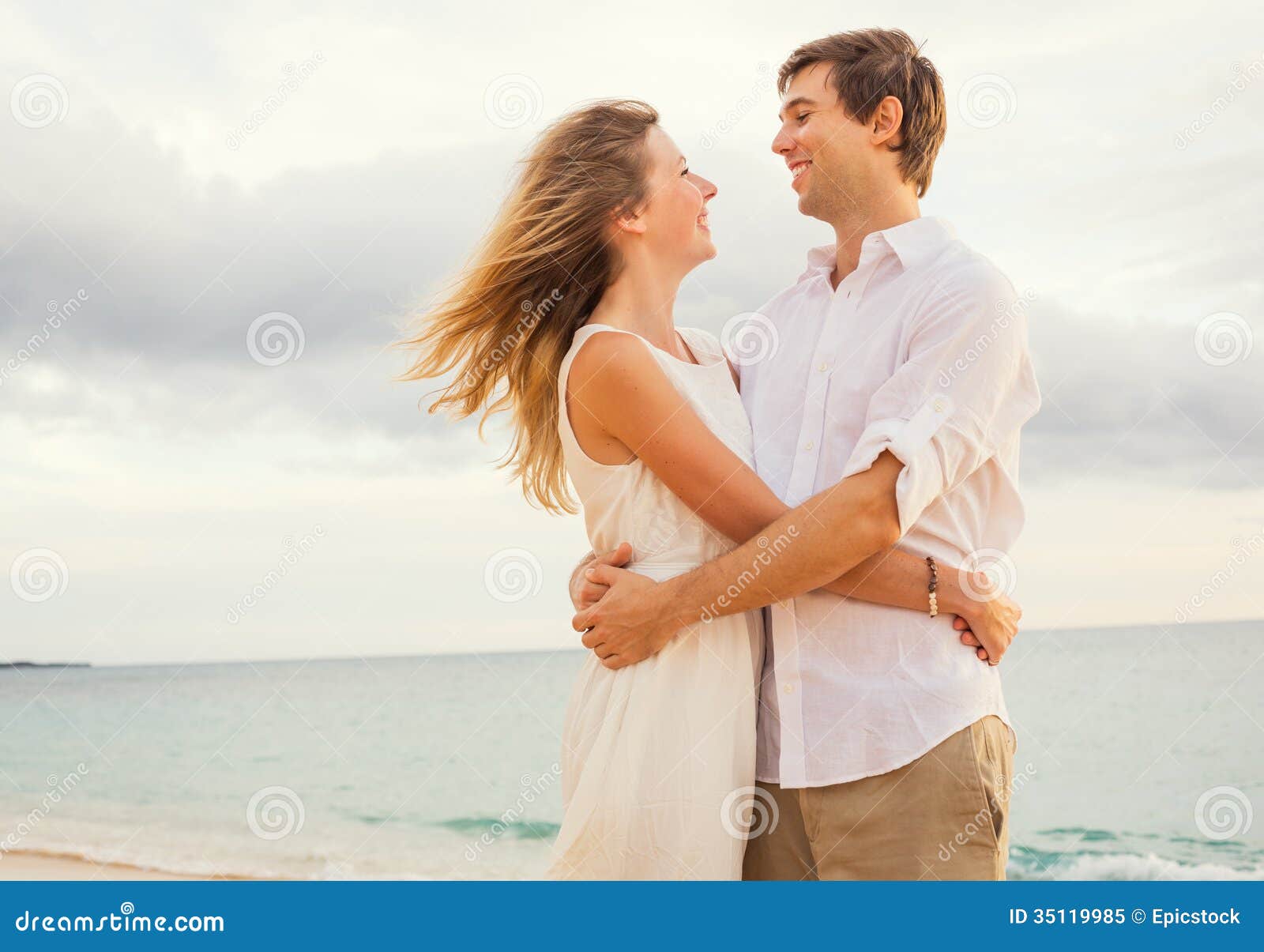 Happy Romantic Couple On The Beach At Sunset Embracing Each Other Stock
