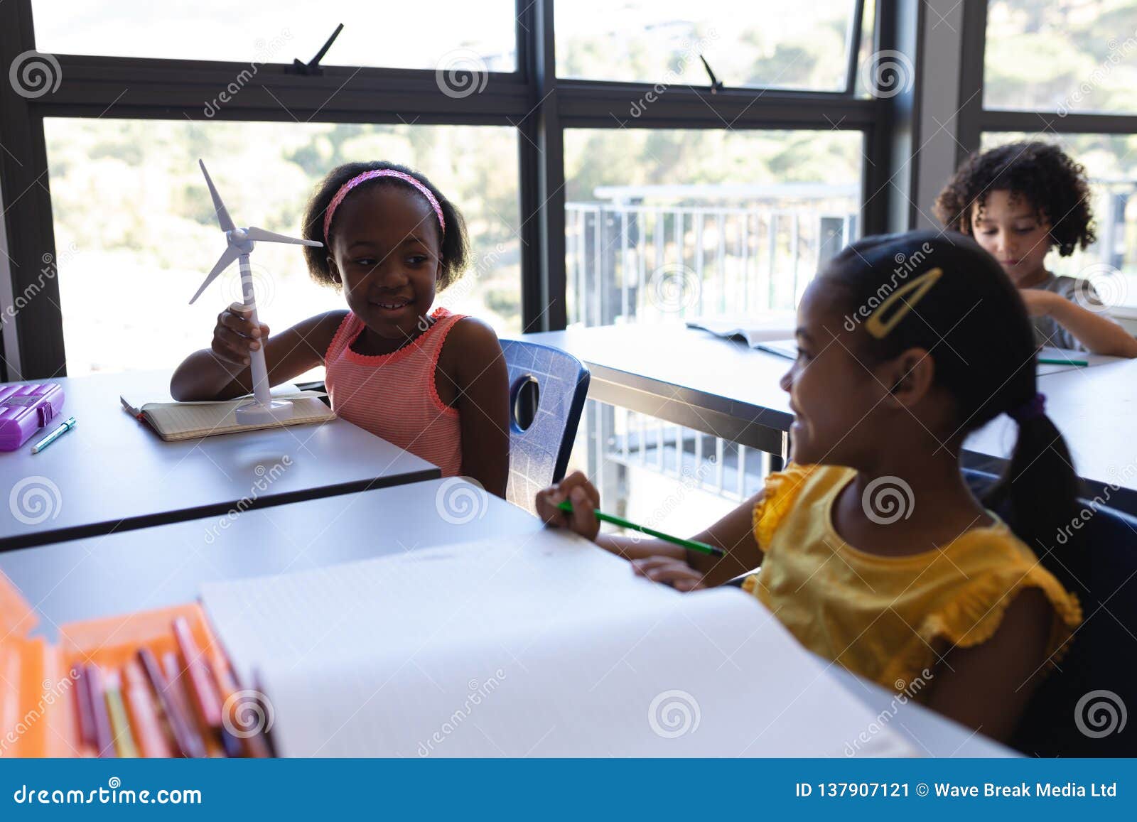Happy Schoolkids Talking with Each Other at Desk in Classroom Stock ...