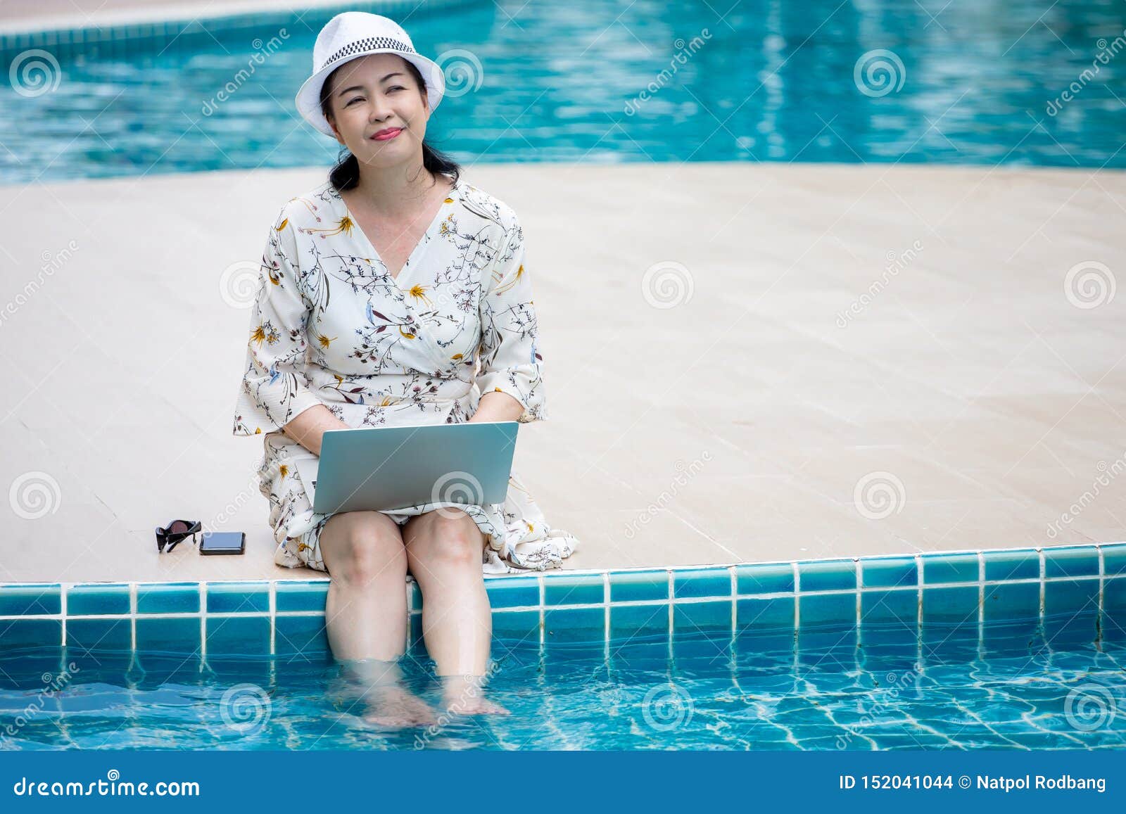 Happy Senior Asian Woman Working On Laptop Computer Sitting At Poolside