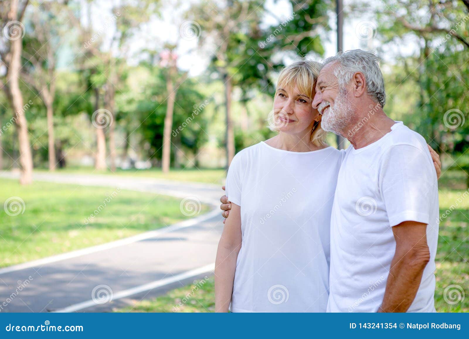 Happy Senior Loving Couple Relaxing At Park Embracing Together In