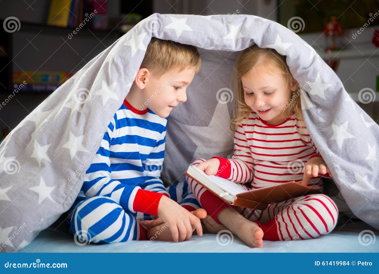 Happy Siblings Reading Book Under Cover Stock Photo - Image of lying ...