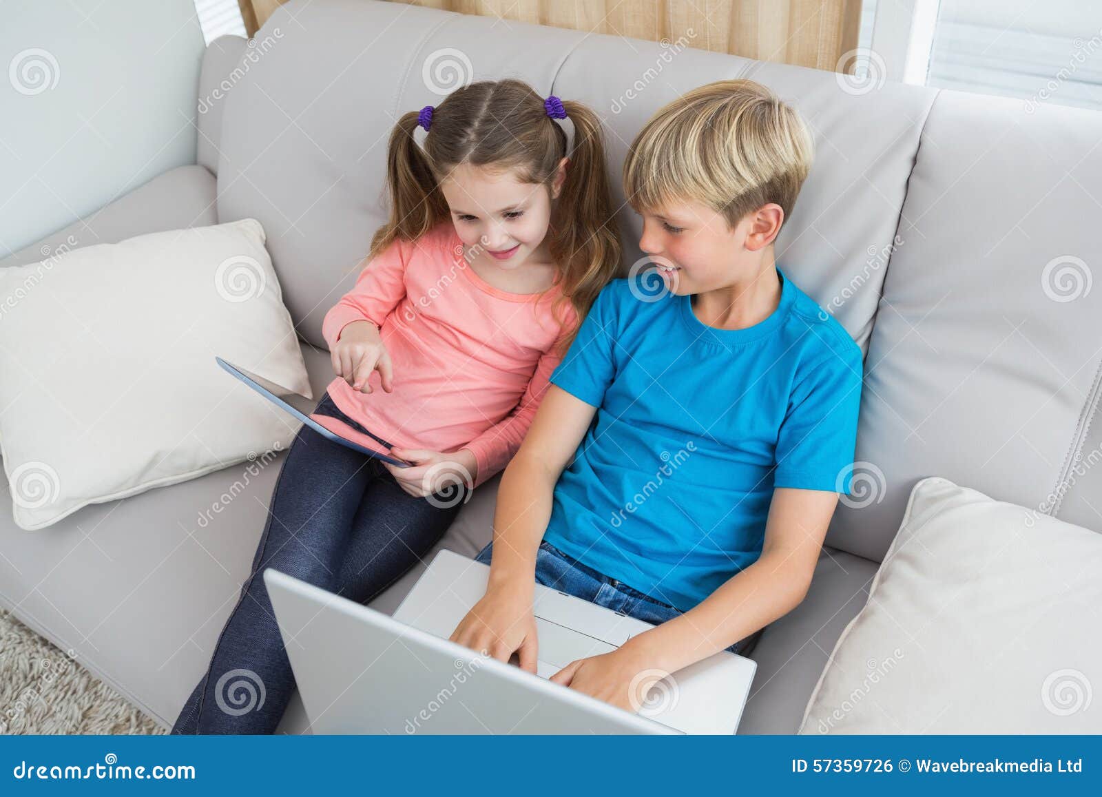 Happy Siblings Using Laptop and Tablet Pc on Sofa Stock Photo - Image ...