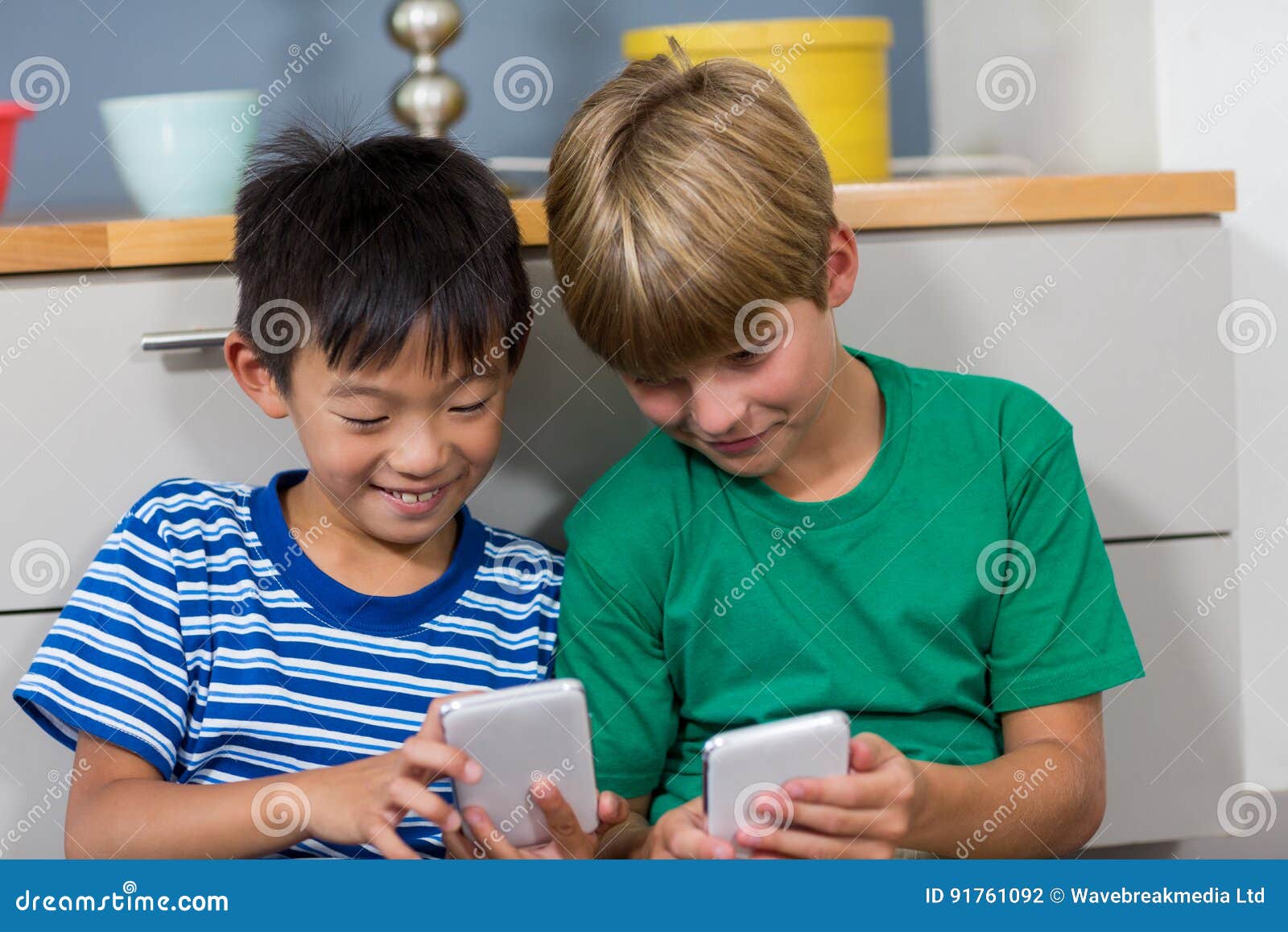 Happy Siblings Using Mobile Phone in Living Room Stock Photo - Image of ...