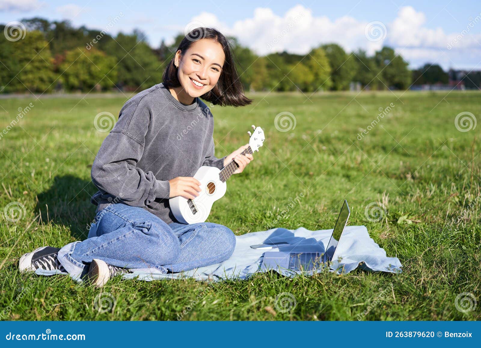 Happy Smiling Asian Girl Enjoying Spring Time Playing Ukulele In Park