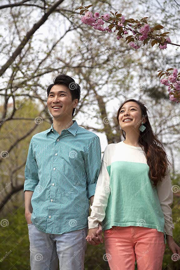 Happy Smiling Young Couple Holding Hands In The Park In Springtime