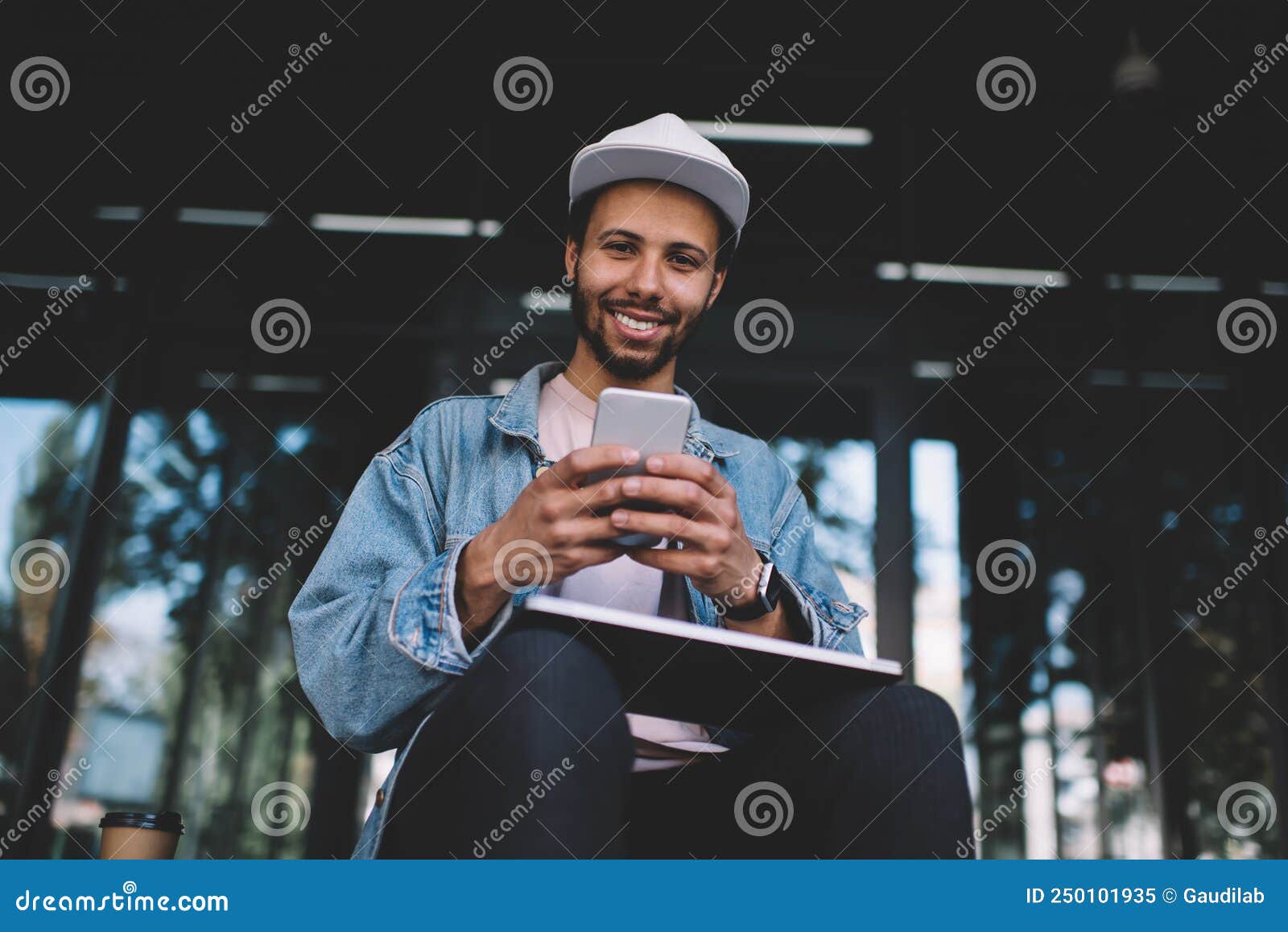 Happy Spanish Programmer with Closed Netbook Device Using Cellphone ...