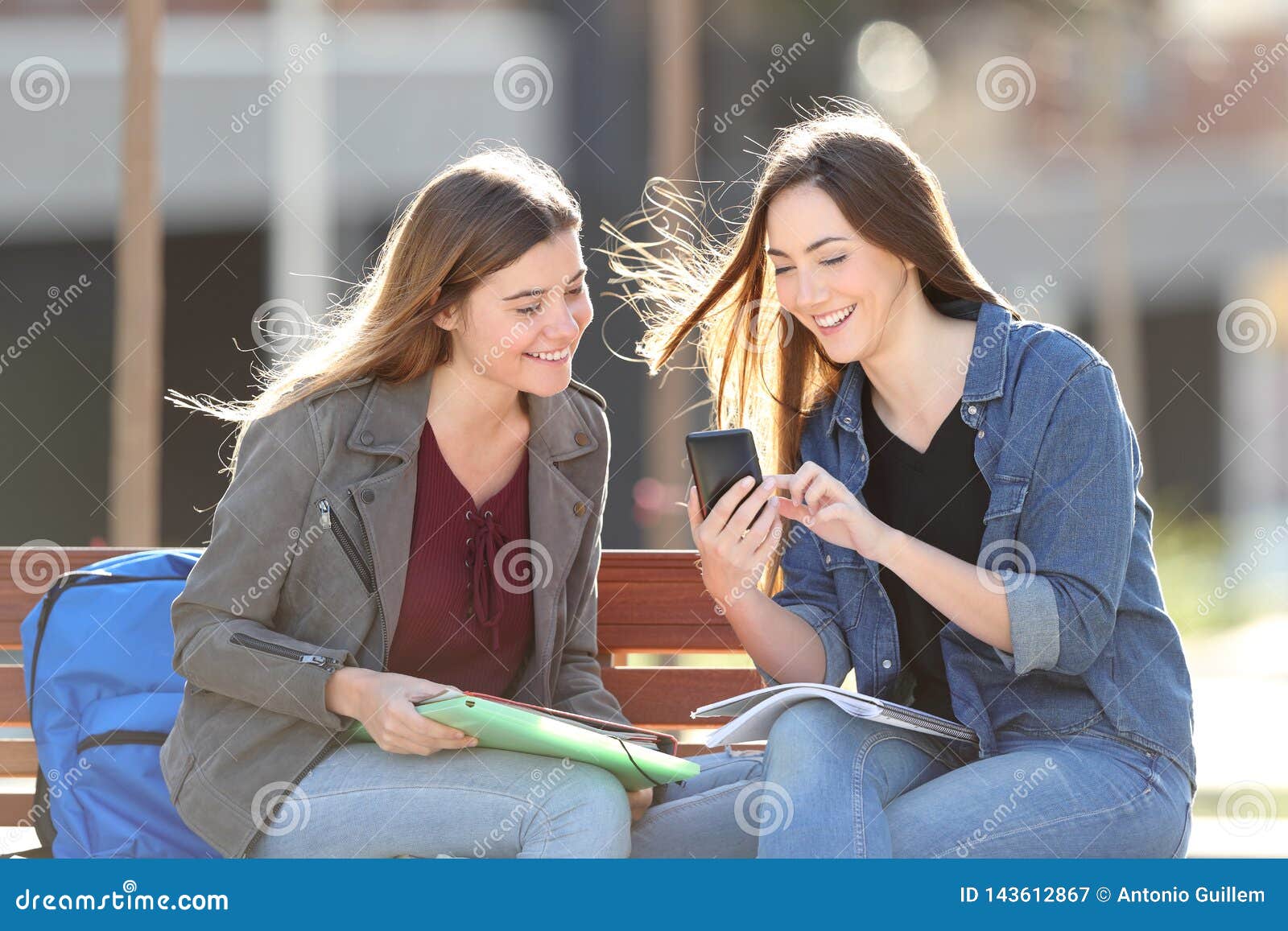 Happy Students Checking Smart Phone on a Bench Stock Image - Image of ...